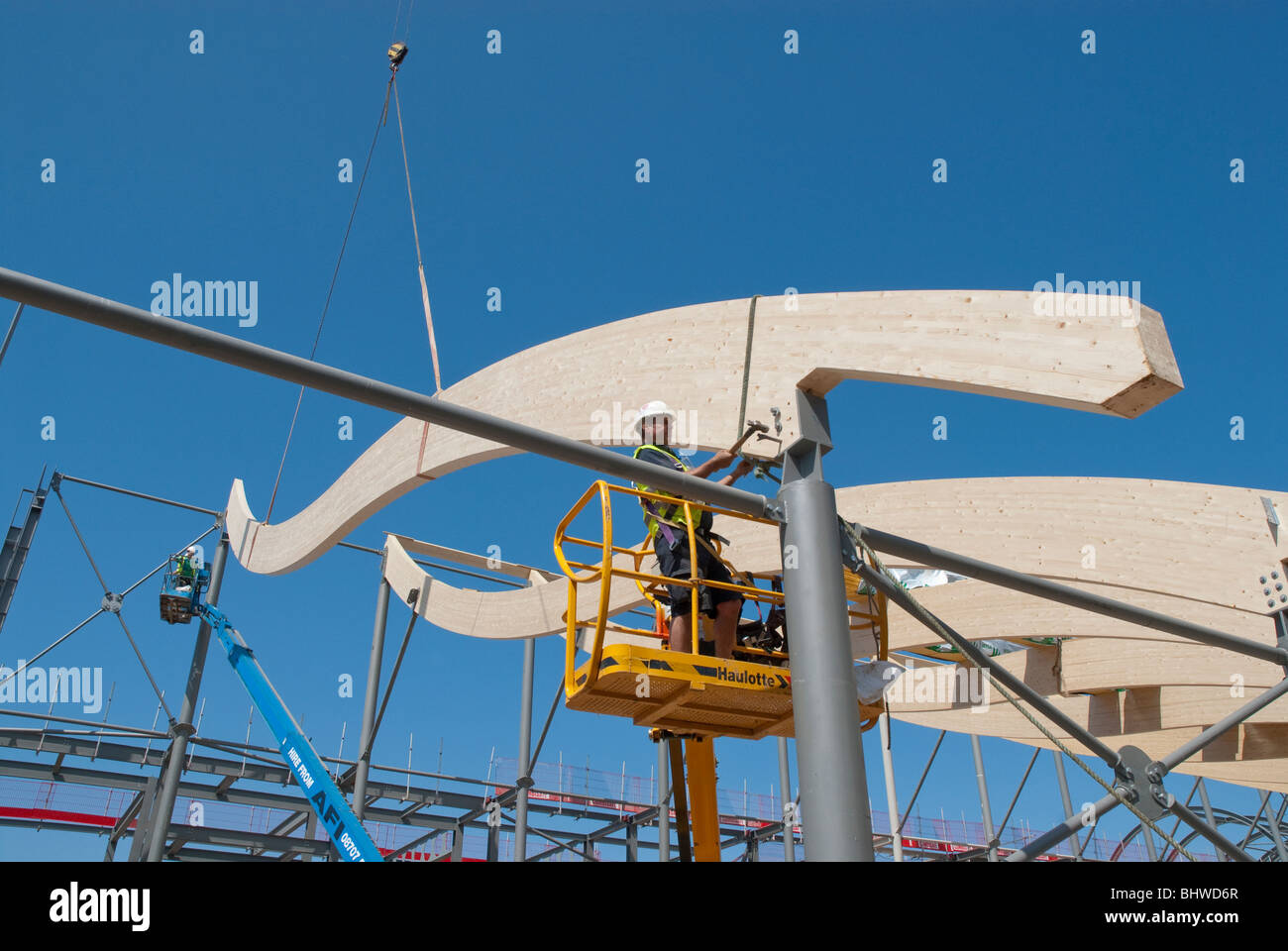 High level Construction workers building laminated wood wave roof on ...