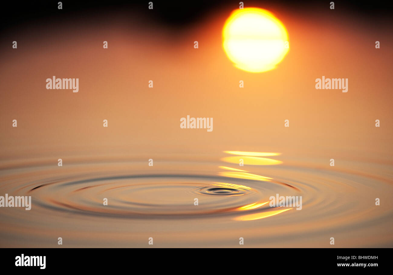 Water drops and ripples in a pool with reflected sunrise background ...