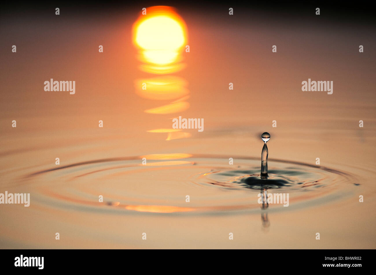 Water drops and ripples in a pool with reflected sunrise background ...