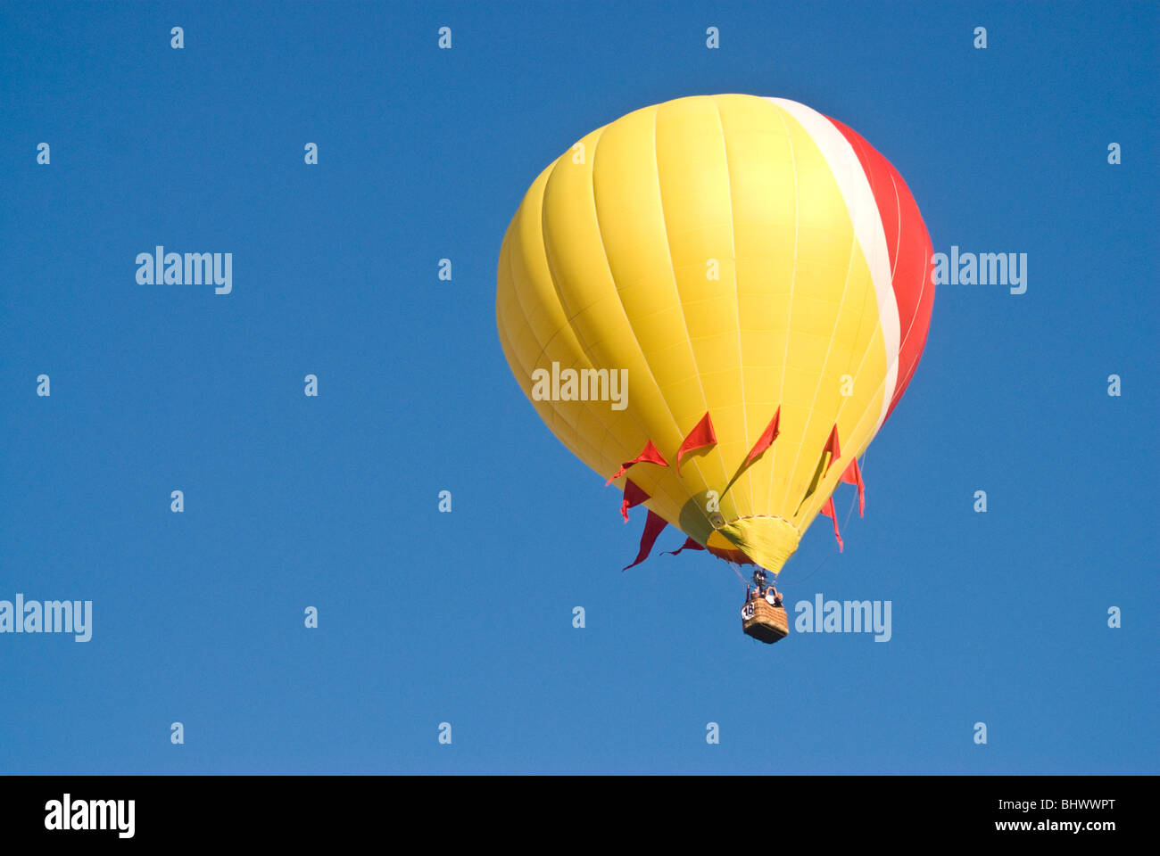 Yellow Hot air balloon flying up in a clear blue sky Stock Photo - Alamy