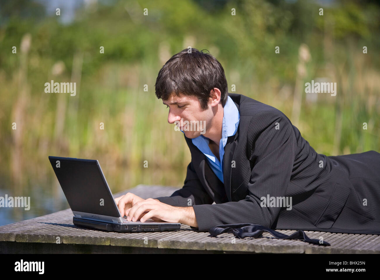 Young man working outside with a laptop Stock Photo - Alamy