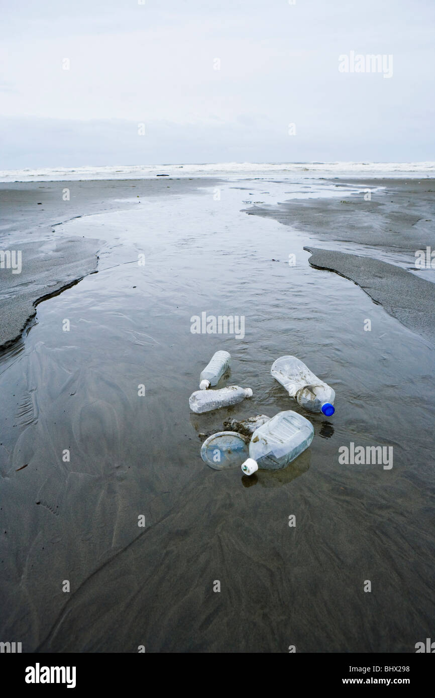 Plastic bottles and lids sitting in a stream as it flows out to the ...