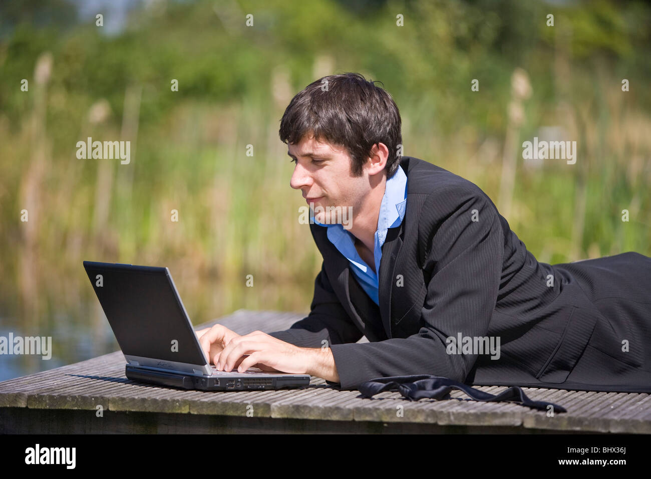 Young man working outside with a laptop Stock Photo - Alamy