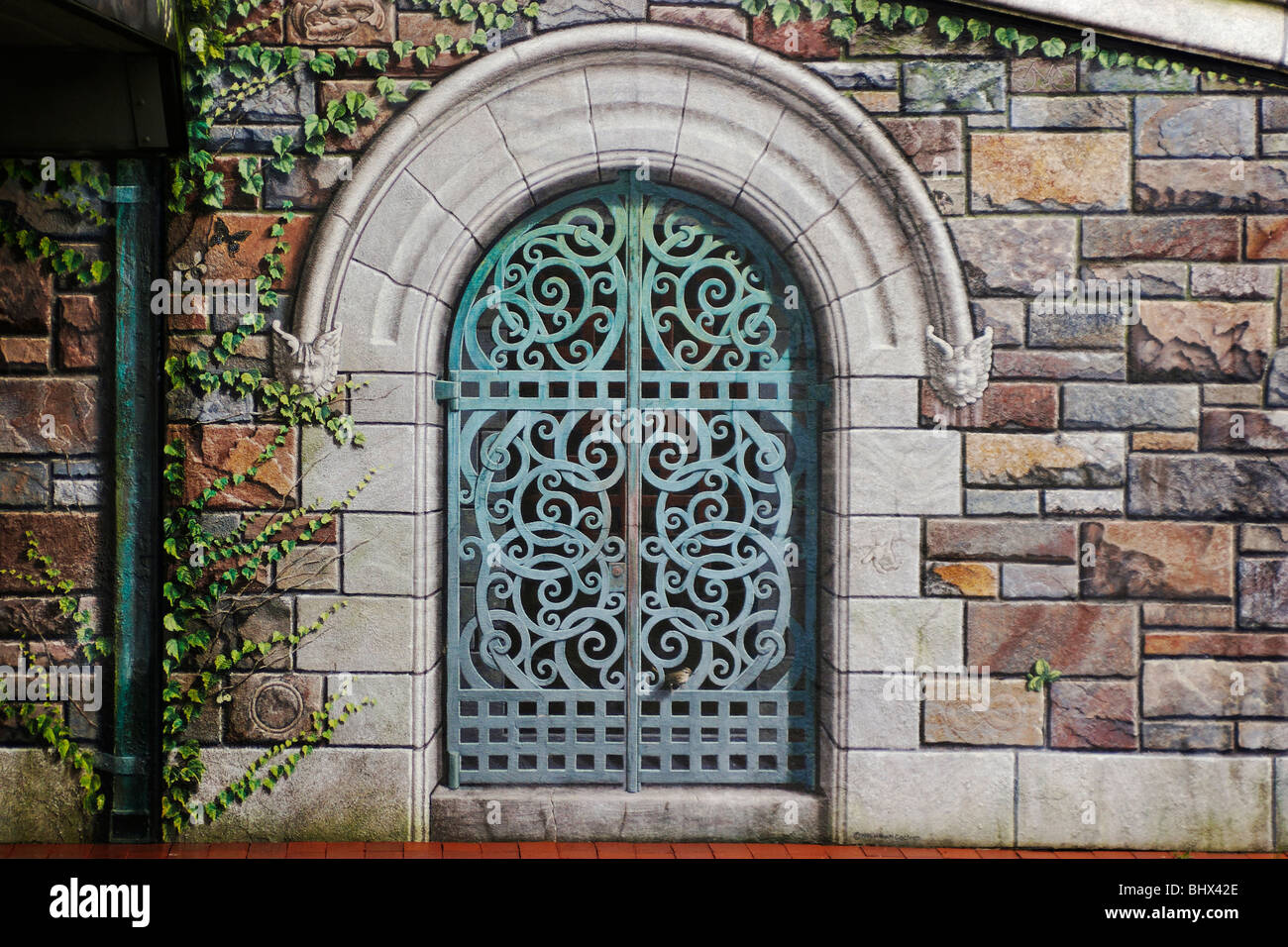A trompe l’oiel bronze gate painted on a wall of the Community Bridge ...