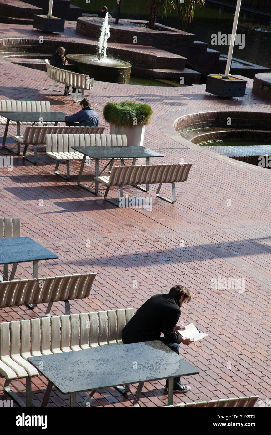 Someone reading a book on seating and tables outside a waterside café ...