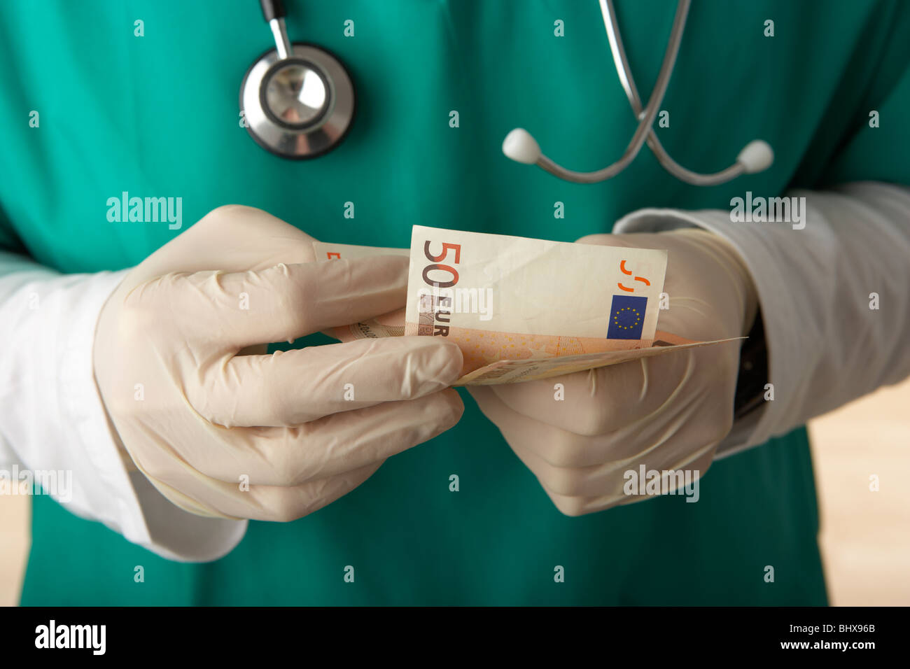 man wearing medical scrubs and stethoscope counting 50 euro banknotes ...