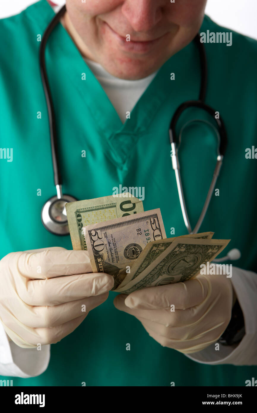 man wearing medical scrubs and stethoscope counting us dollar banknotes ...