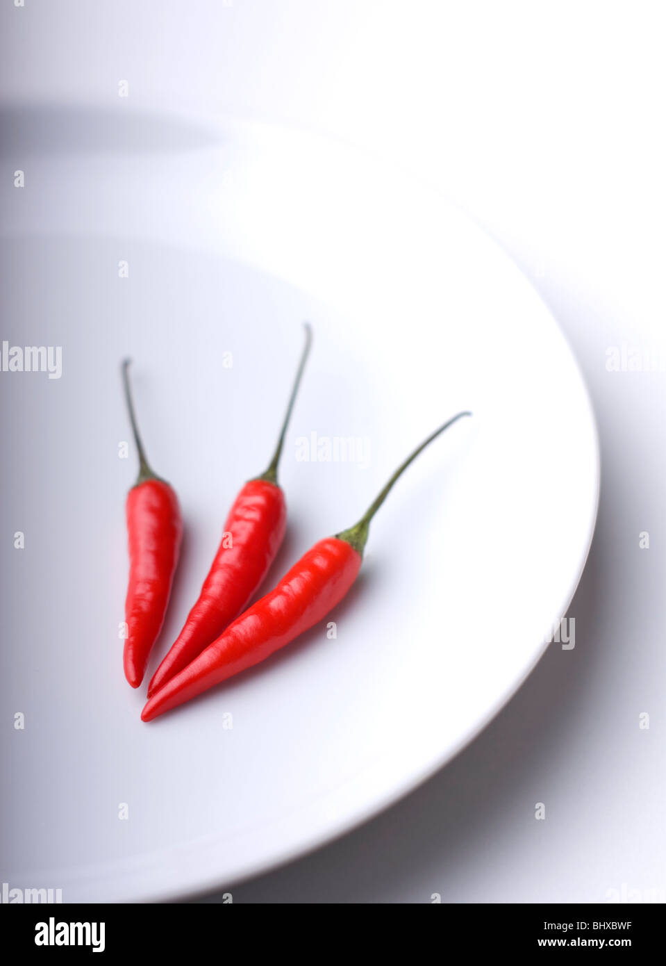 Three chillies on a white plate Stock Photo - Alamy