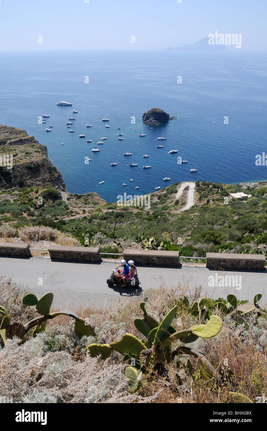 A tourist couple riding on a moped on the island of Salina, overlooking ...