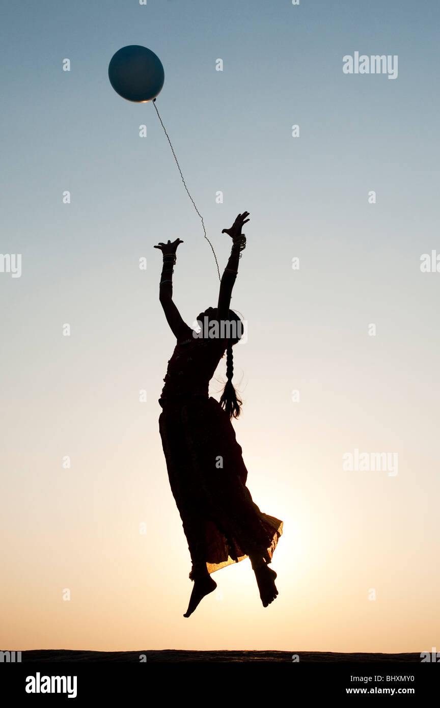 Silhouette of a young Indian girl catching a balloon at sunset Stock ...