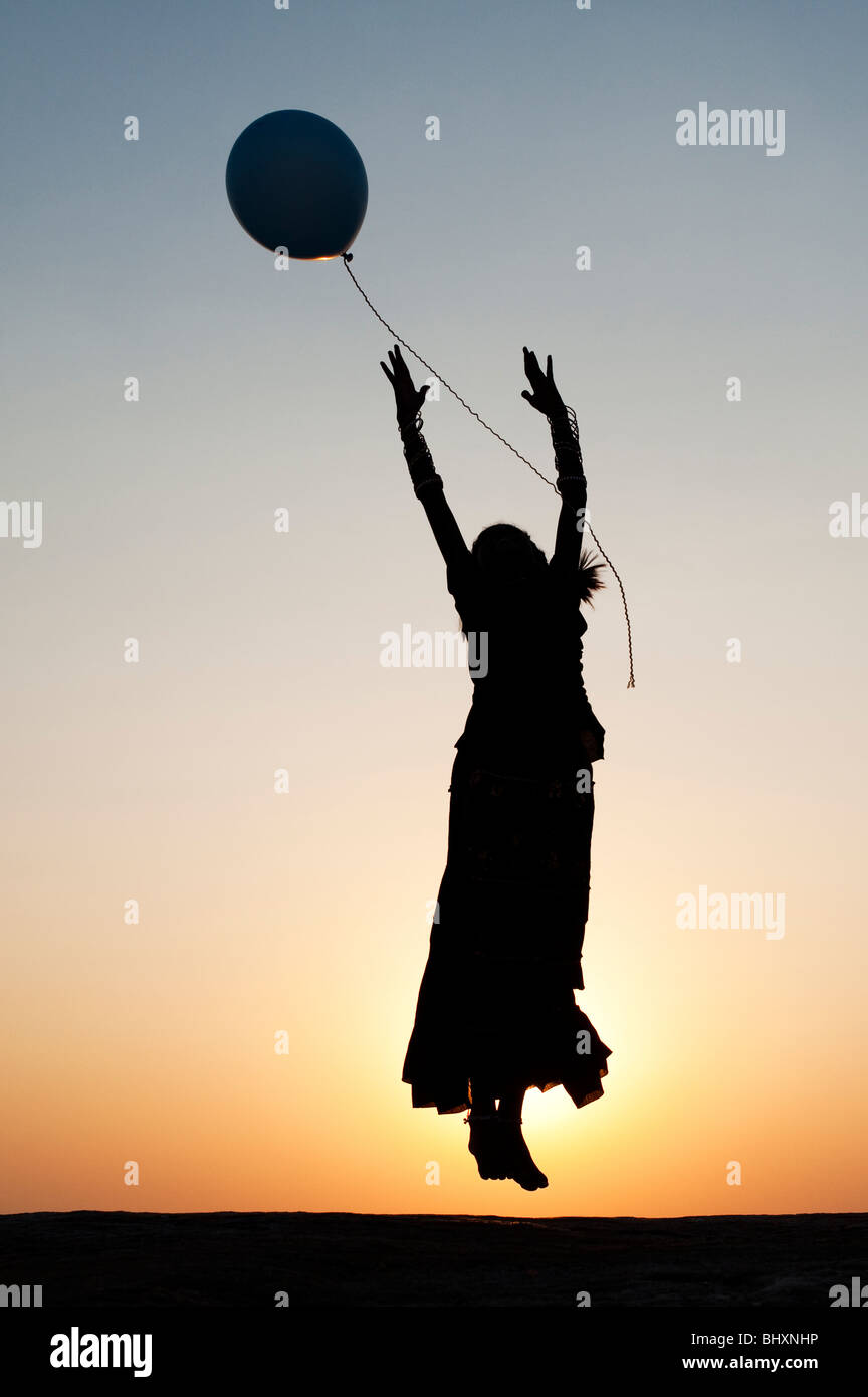 Silhouette of a young Indian girl catching a balloon at sunset Stock ...