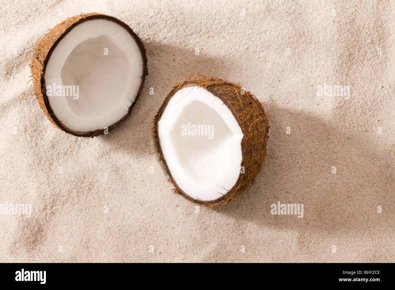 two half coconut lying in sand Stock Photo - Alamy