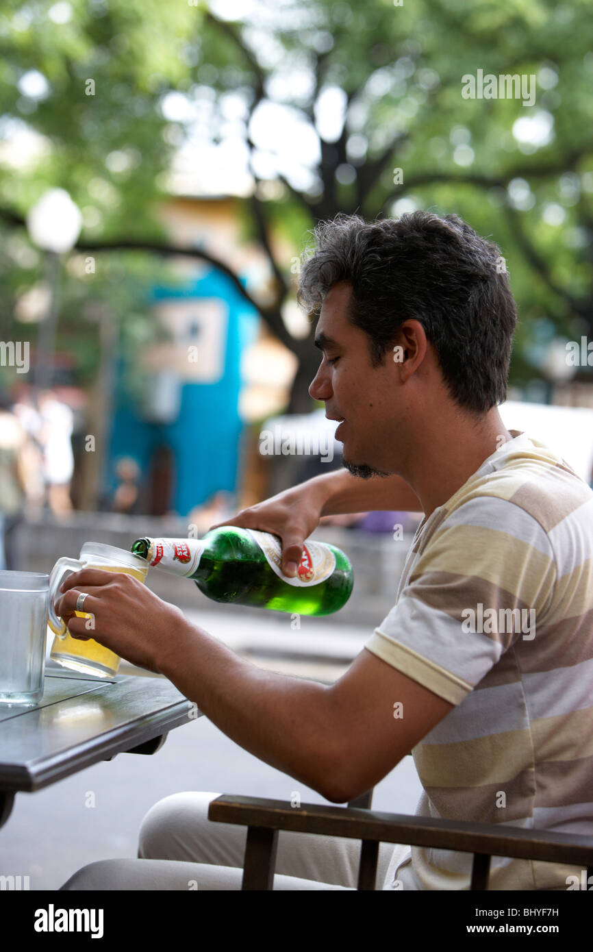 early thirties hispanic man pouring a glass of beer at an outdoor cafe ...