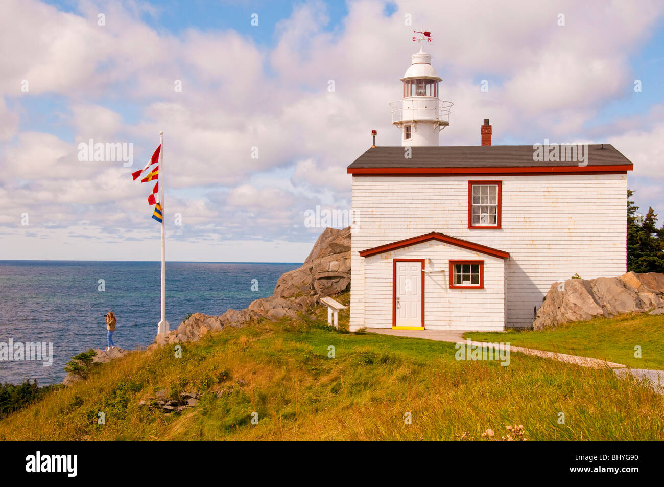 NEWFOUNDLAND, Woman taking picture below flags, Lobster Cove Lighthouse ...