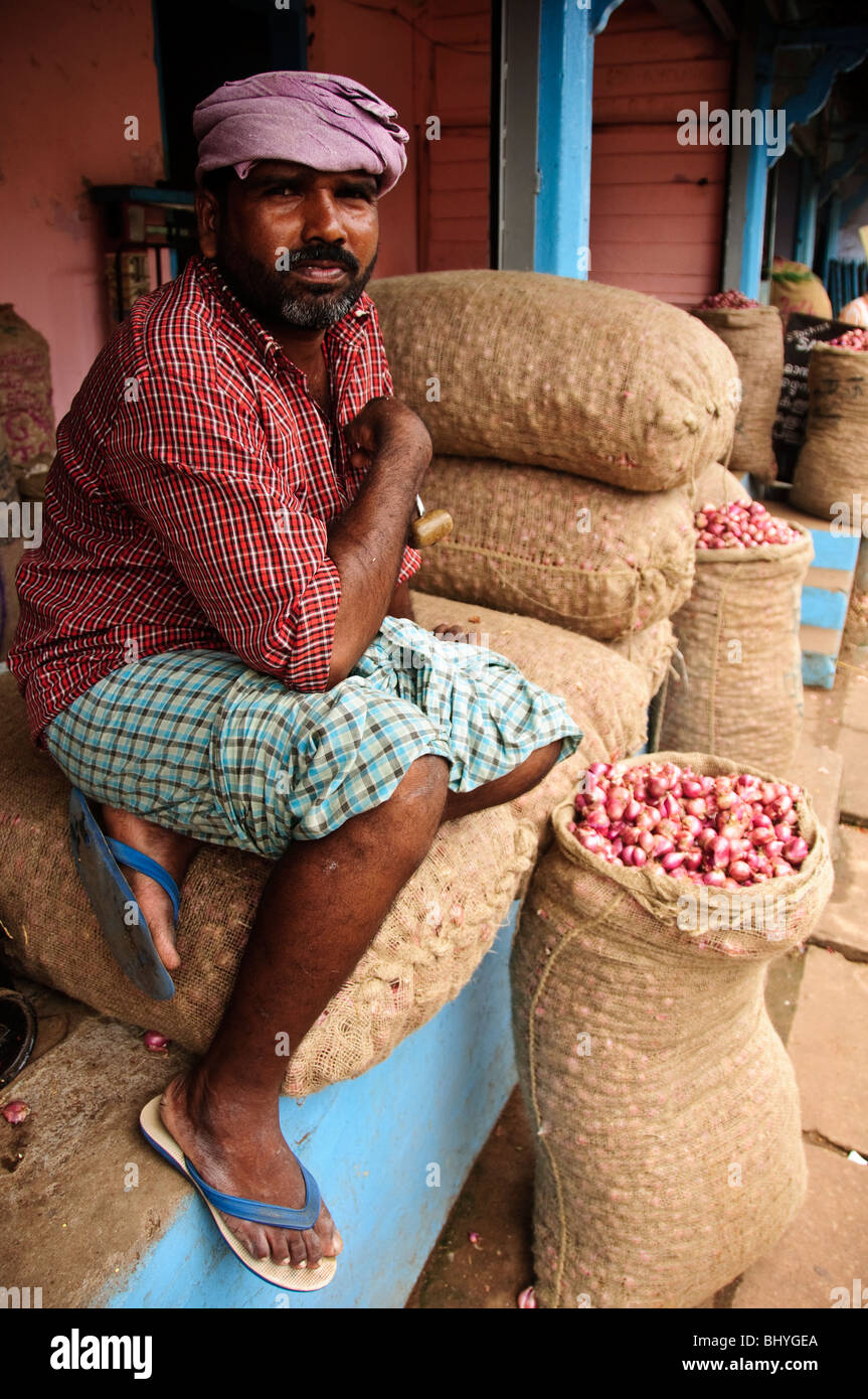A porter resting on bags of shallots. Kollam, Kerala, India Stock Photo ...