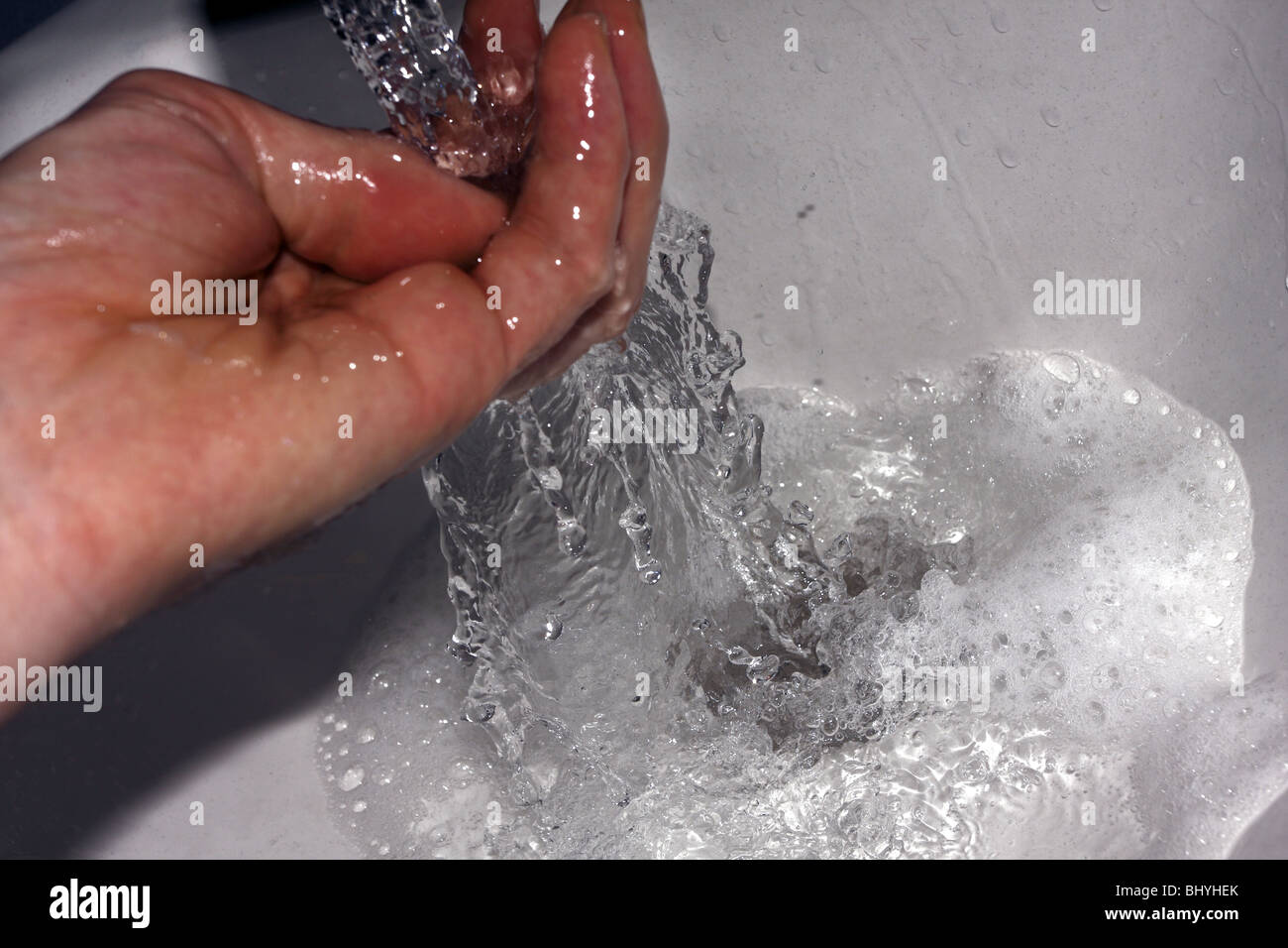 Left hand under stream of clear water in sink Stock Photo - Alamy