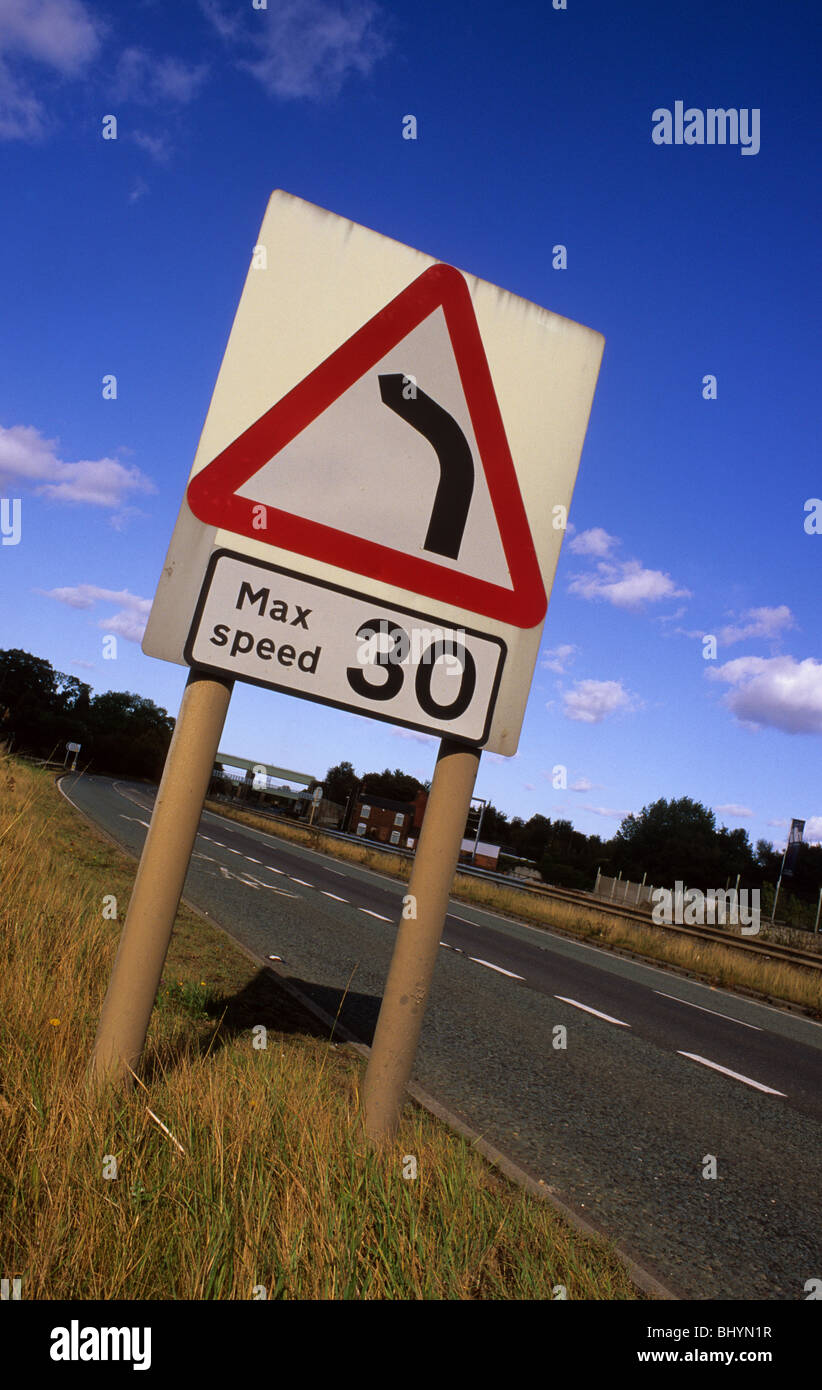 warning sign of 30 mph speed limit and sharp left hand bend in the road ...