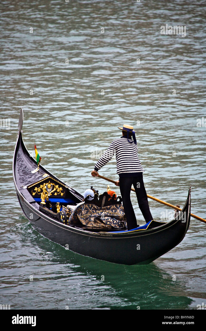 A gondolier rowing his gondola and tourists along the Grand Canal in ...