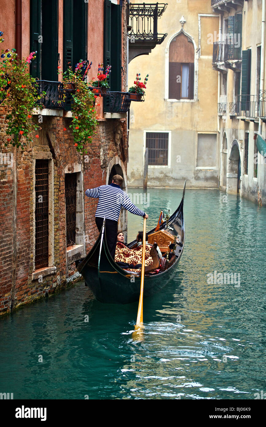 A gondolier rowing his gondola and tourists along the Grand Canal in ...
