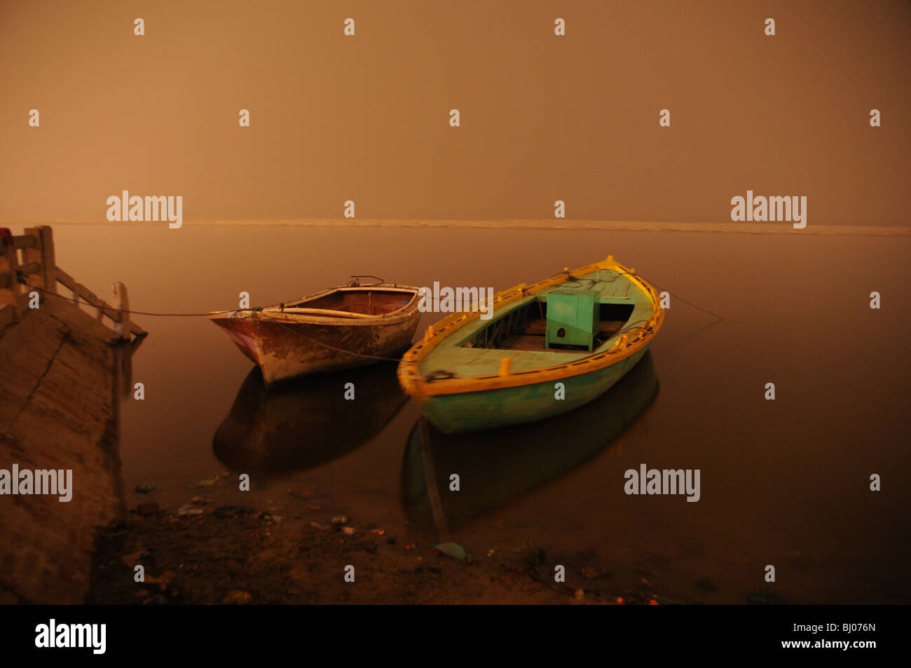 two boats float peacefully at the edge of the ganges river in varanasi ...