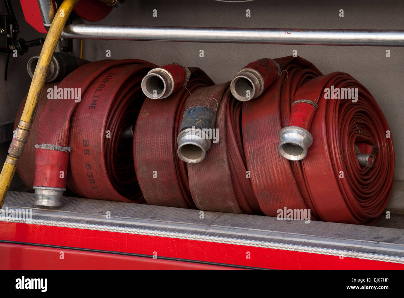 Rolled fire hose in locker ready for use Stock Photo - Alamy