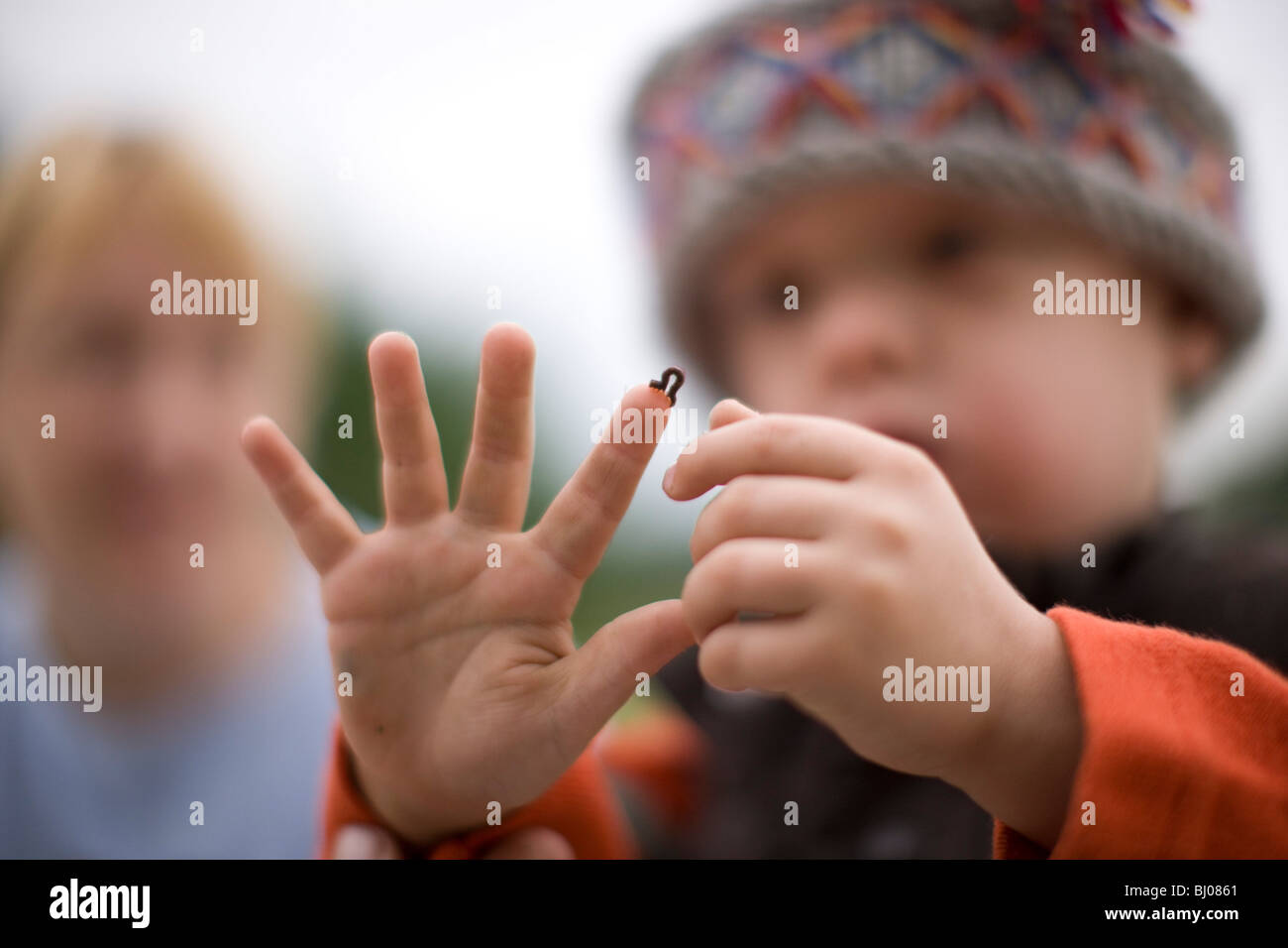 Young boy looking at an inchworm crawling on his hand Stock Photo - Alamy