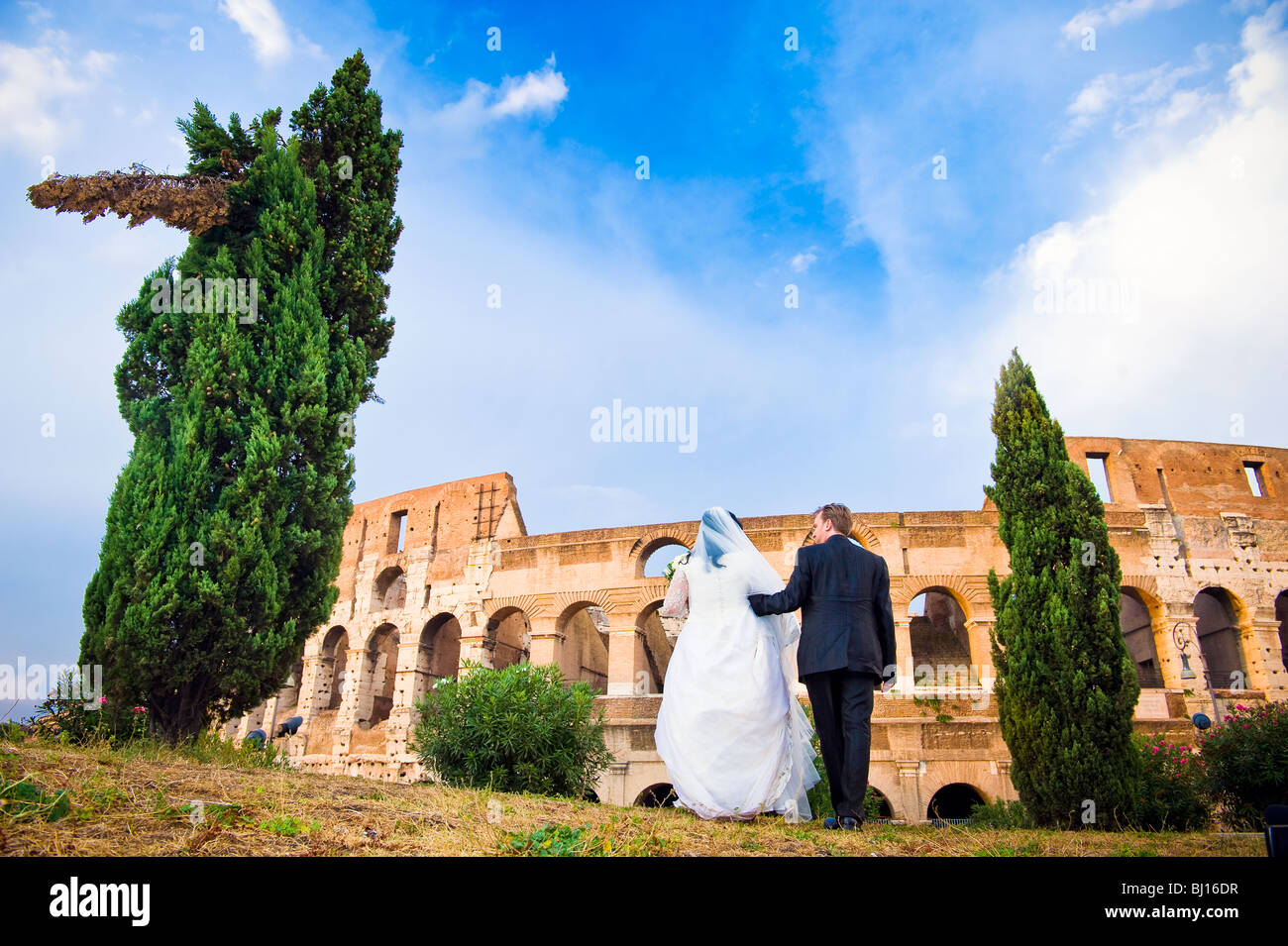 Rear view of bride and groom standing outside the Coliseum, Rome, Italy ...