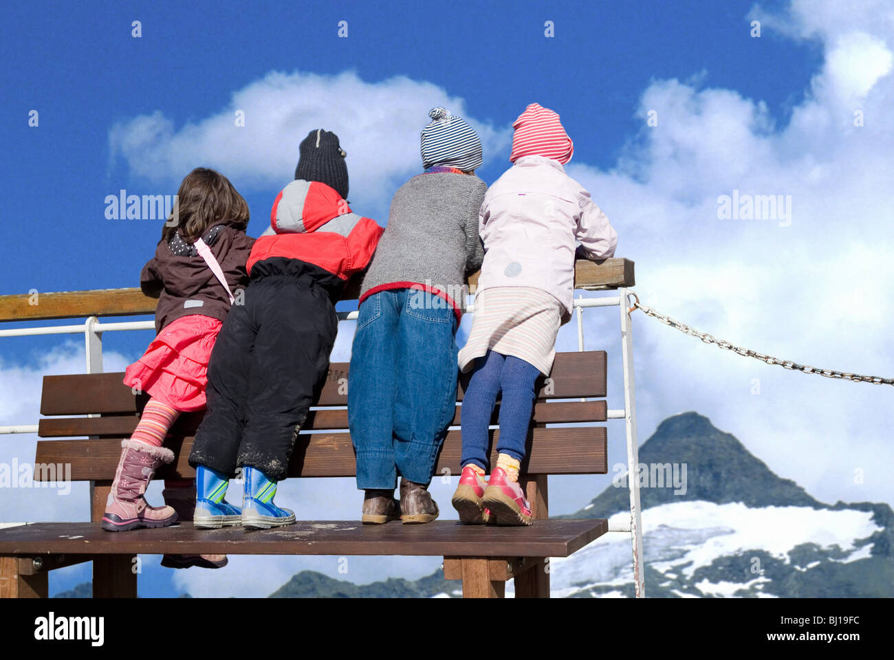 Children standing on a bench and looking at the mountains Stock Photo ...
