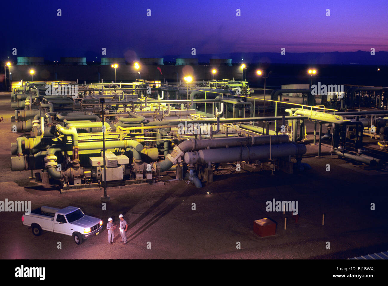 two utility workers standing in front of a pickup truck with a ...