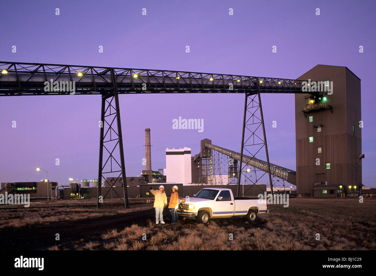 two utility workers standing by a pickup truck with a coal conveyors in ...