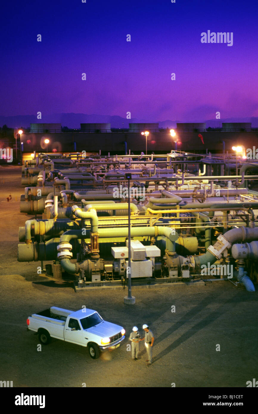 two utility workers standing in front of a pickup truck with a ...