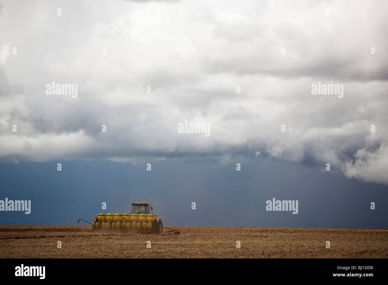 A tractor planting with a storm on the field Stock Photo - Alamy