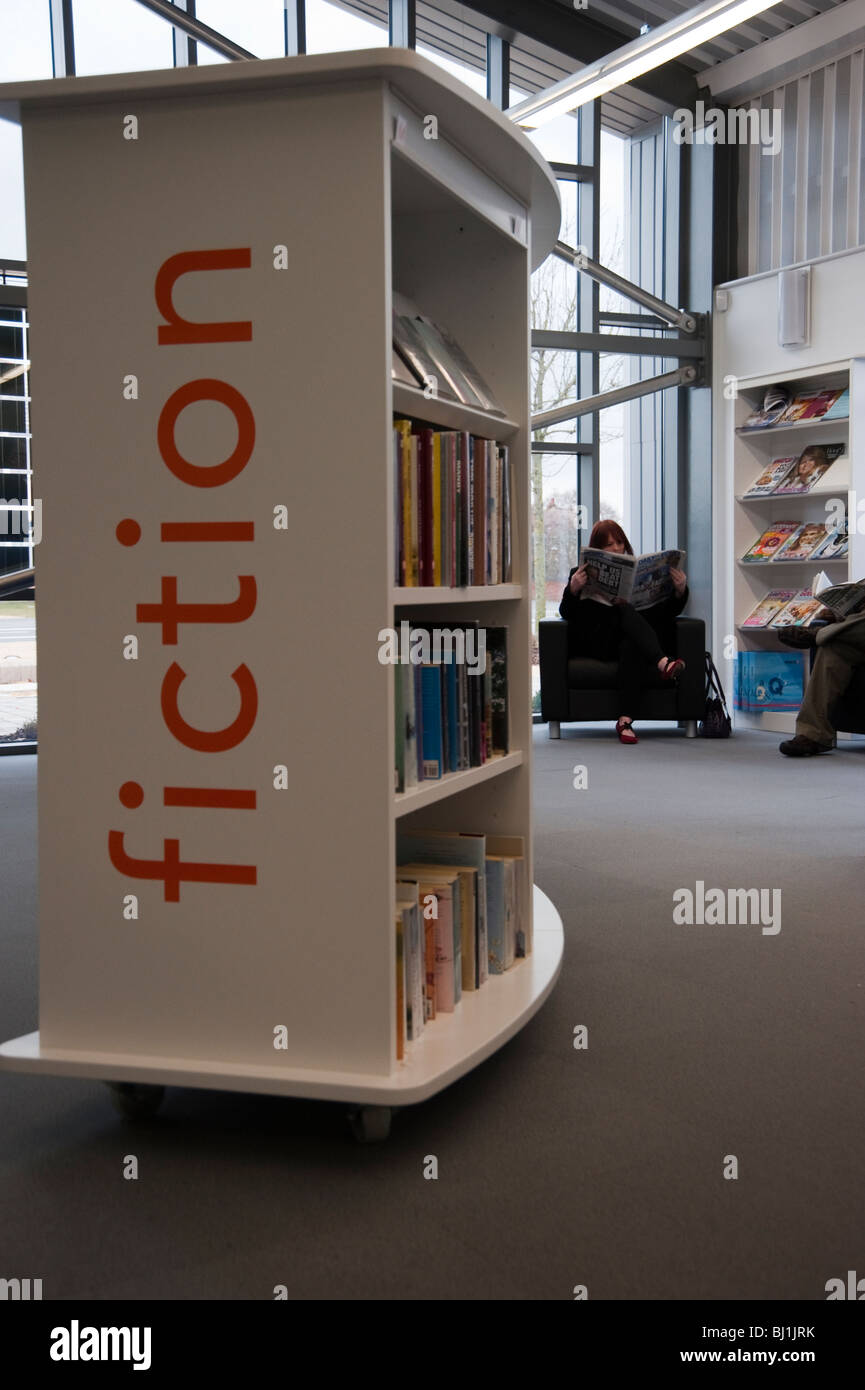 Bookshelves, and a woman sitting reading a newspaper, in Hamworthy ...