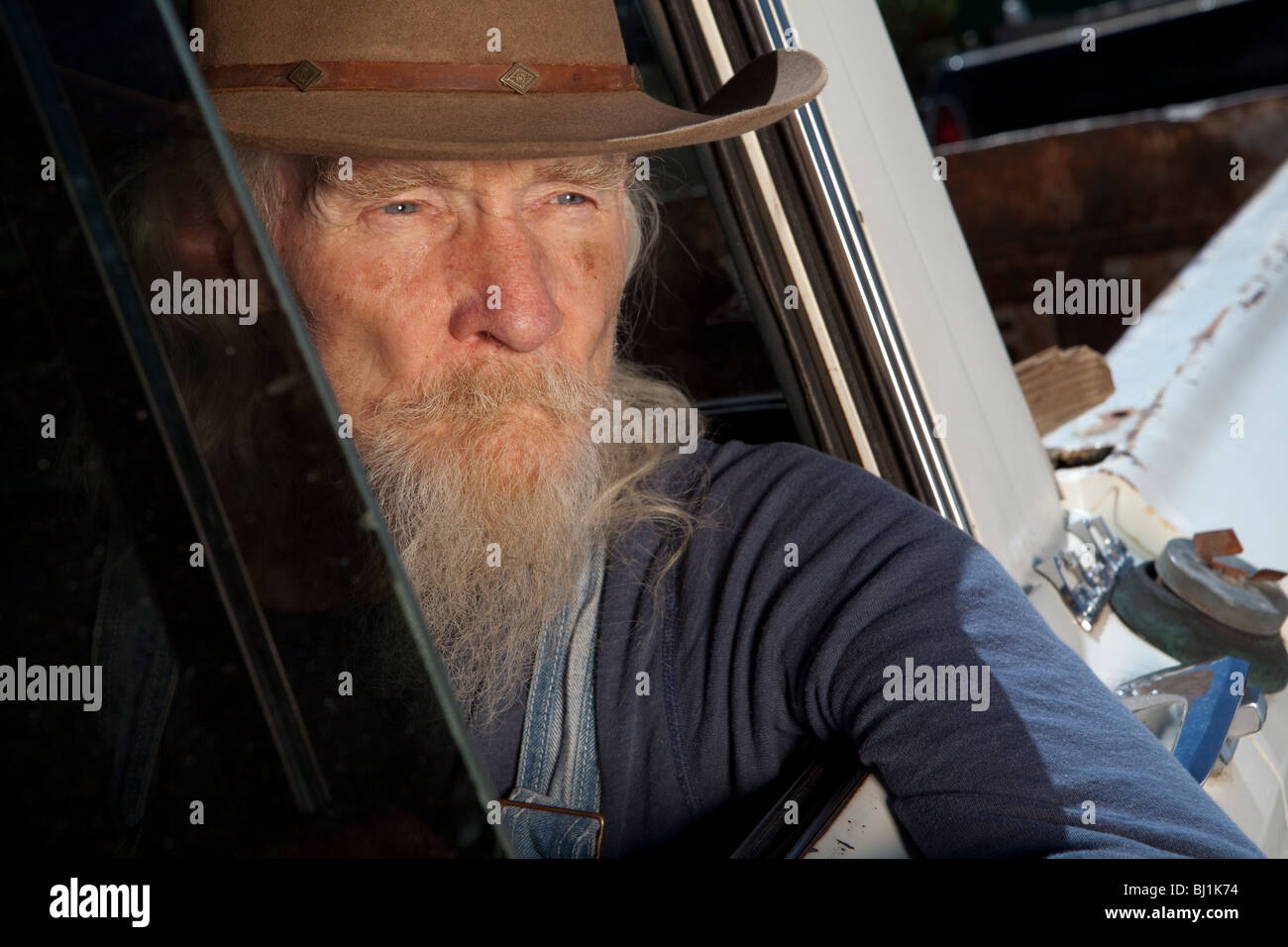 An elderly man with a white beard driving a pickup truck and staring ...