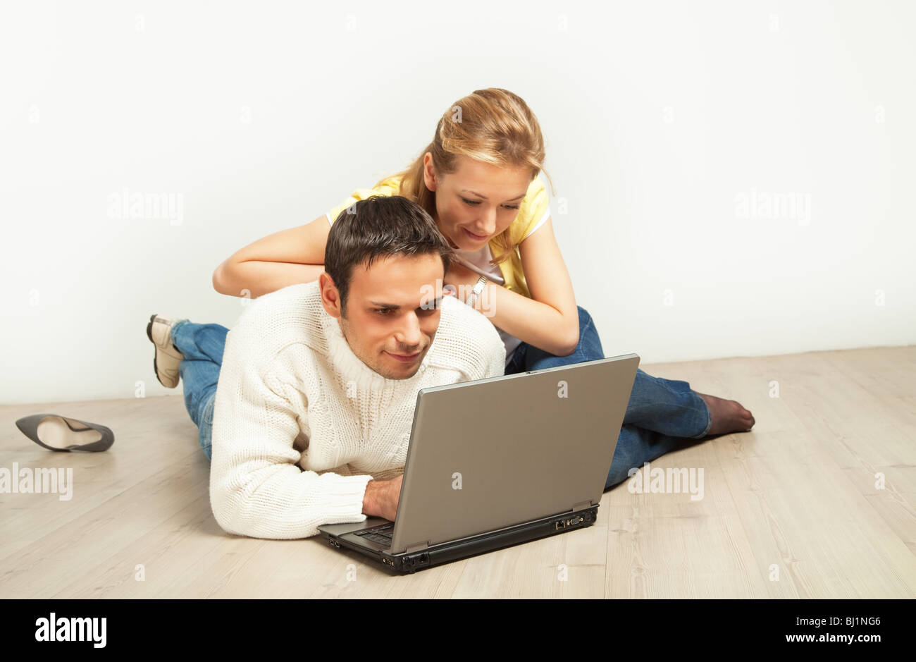 Happy young man and woman sitting together and looking at computer ...