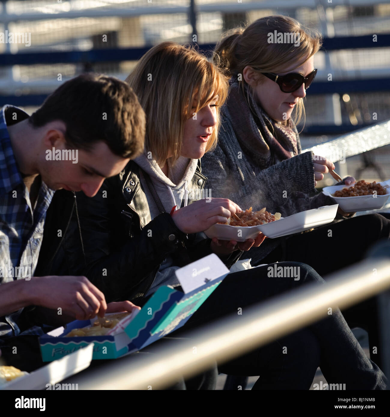 Three young people eating chips and baked beans outdoors, UK Stock ...