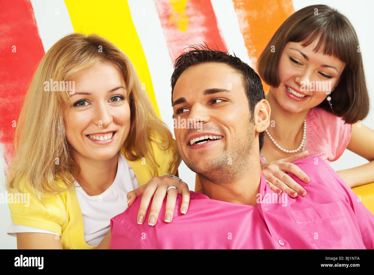 Group of three happy people sitting on sofa in a colorfully painted ...