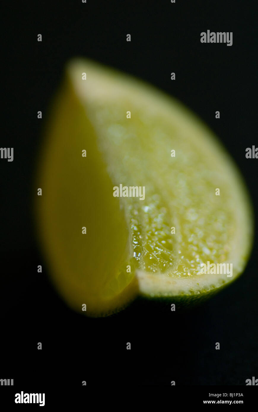 A macro image of a wedge of Lime on a black background Stock Photo - Alamy