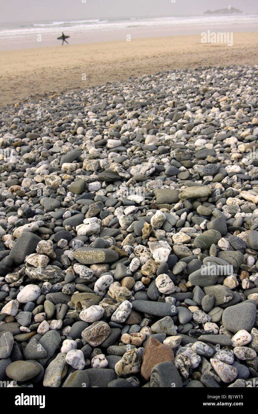 Pebble beach with surfer carrying surfboard in background Godrevy ...