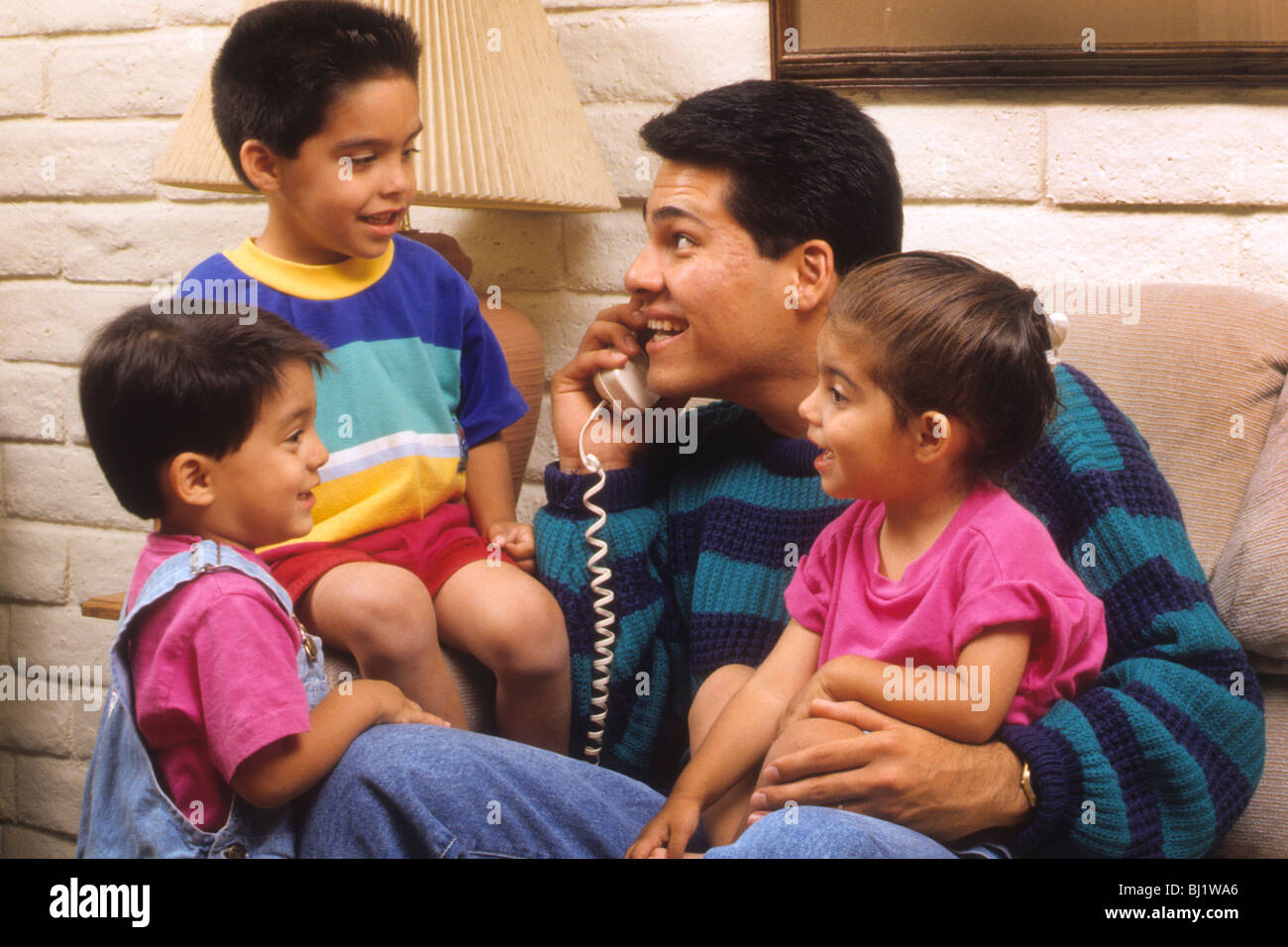Hispanic father and three children share telephone conversation with ...