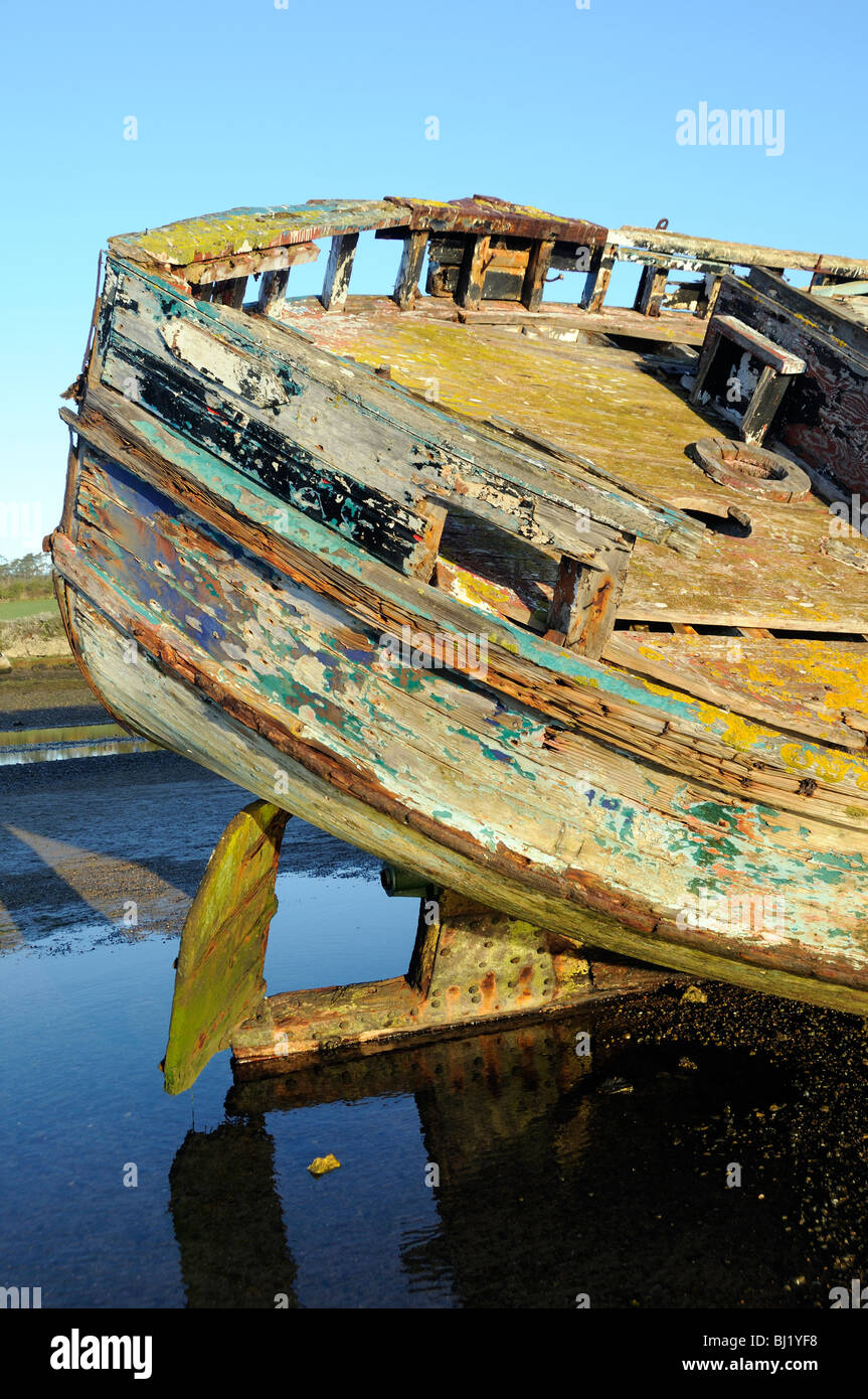 The rotting hull of a timber fishing boat lies on the beach. City Dulas ...