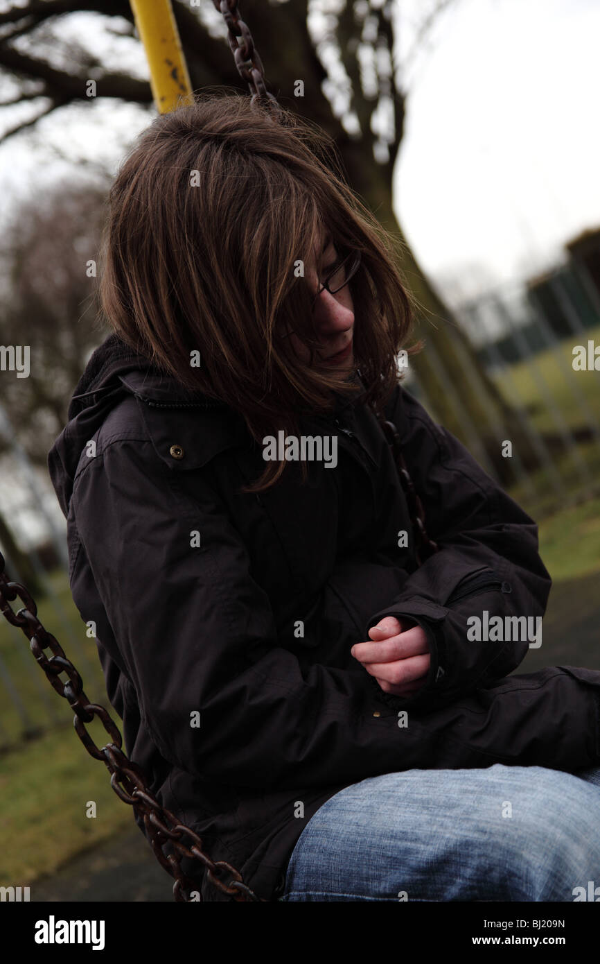 young girl sat on a swing looking sad Stock Photo - Alamy