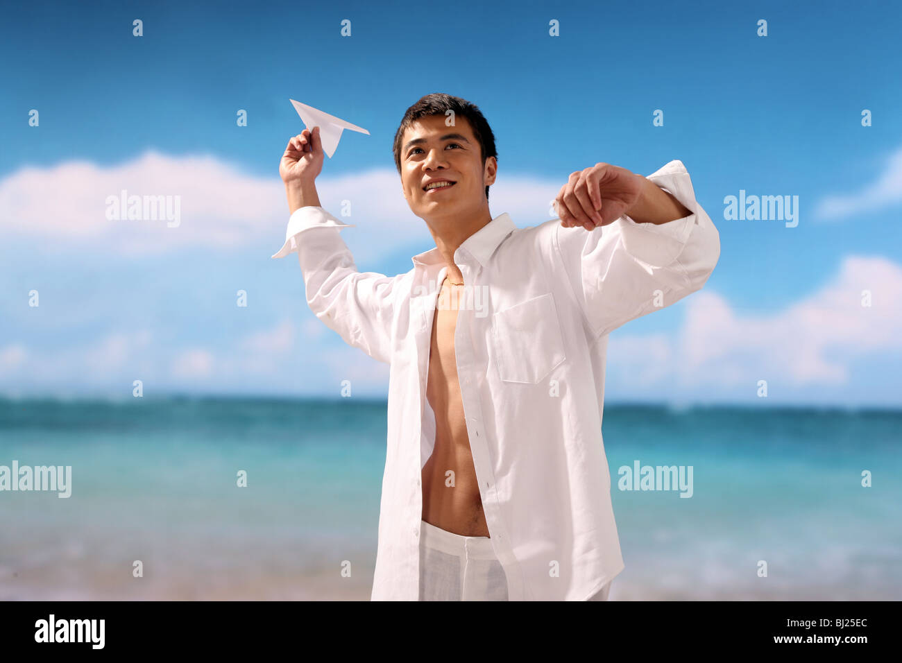 Man playing paper airplane on beach,smiling Stock Photo - Alamy