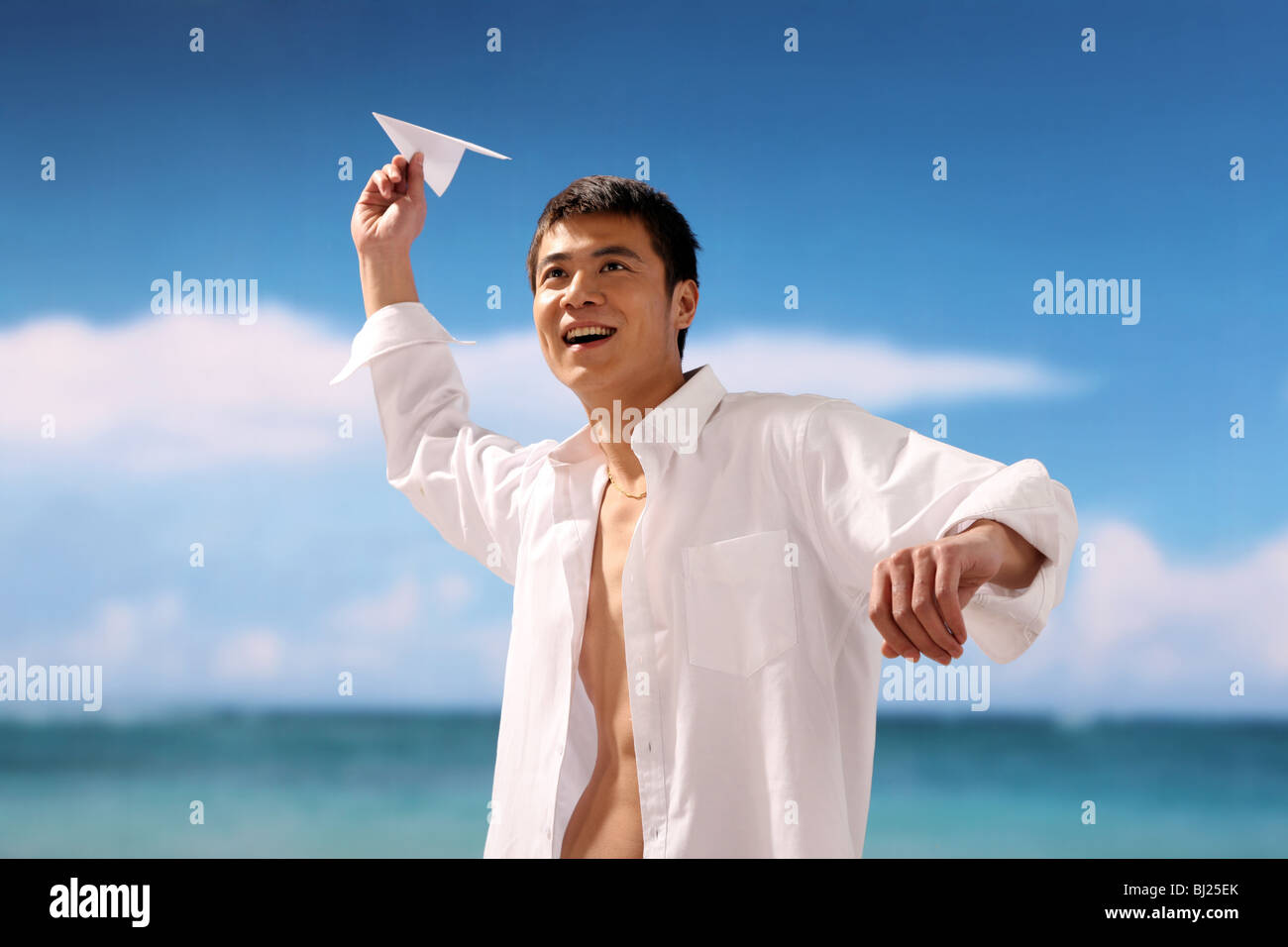 Man playing paper airplane on beach,smiling Stock Photo - Alamy