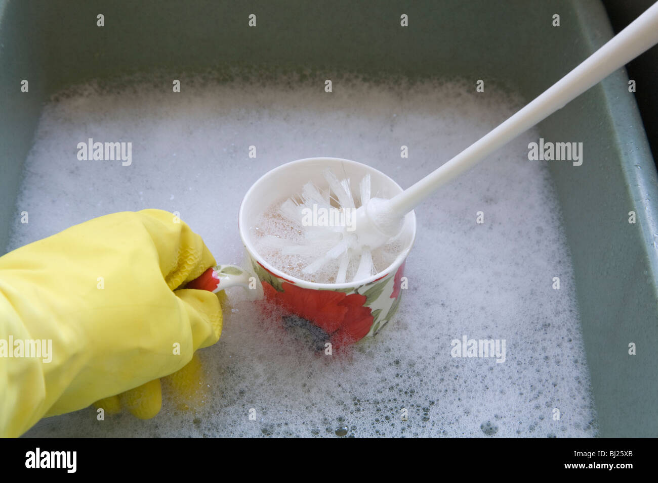 Close up woman using a brush to clean the inside of a ceramic mug ...