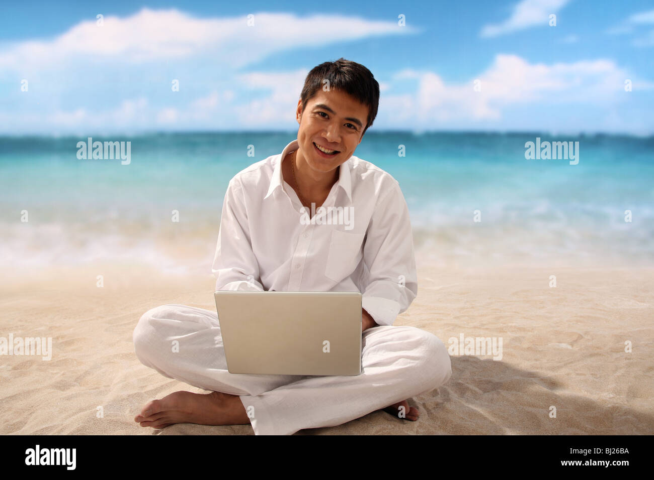 Young man sitting on beach,using laptop Stock Photo - Alamy