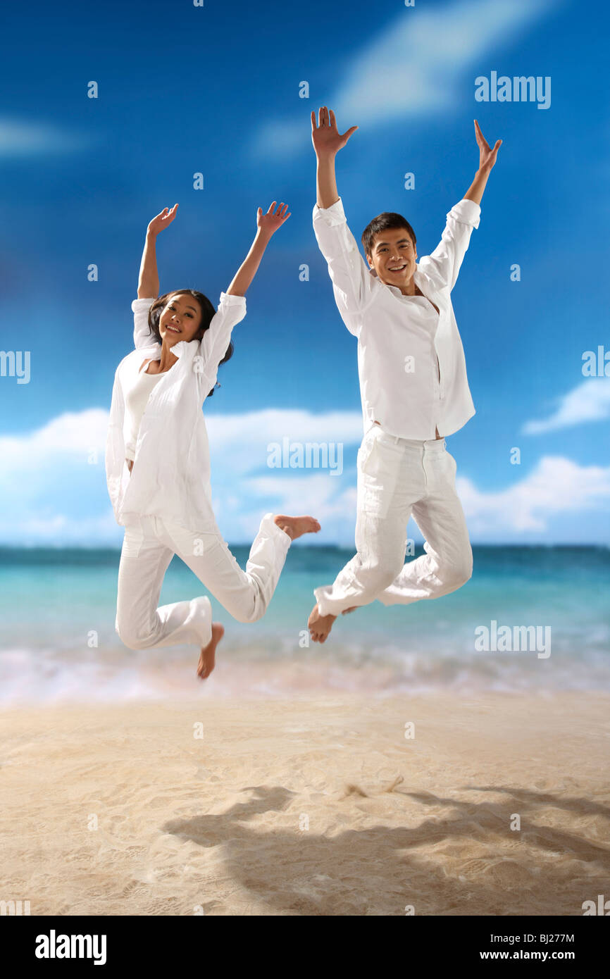 Young couple jumping on beach,smiling Stock Photo - Alamy