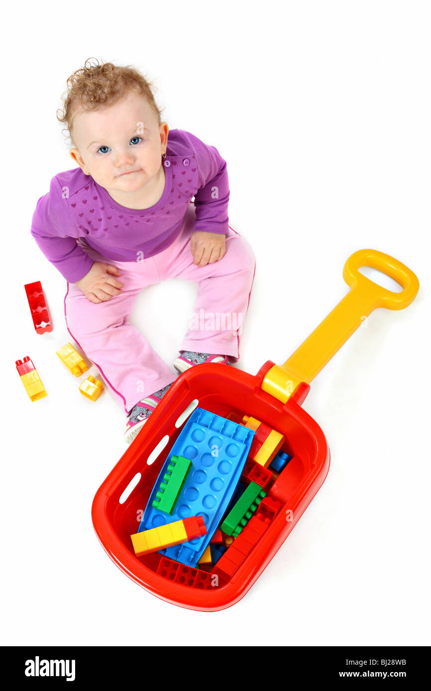 Baby girl sitting on floor with brick toys looking at camera isolated ...