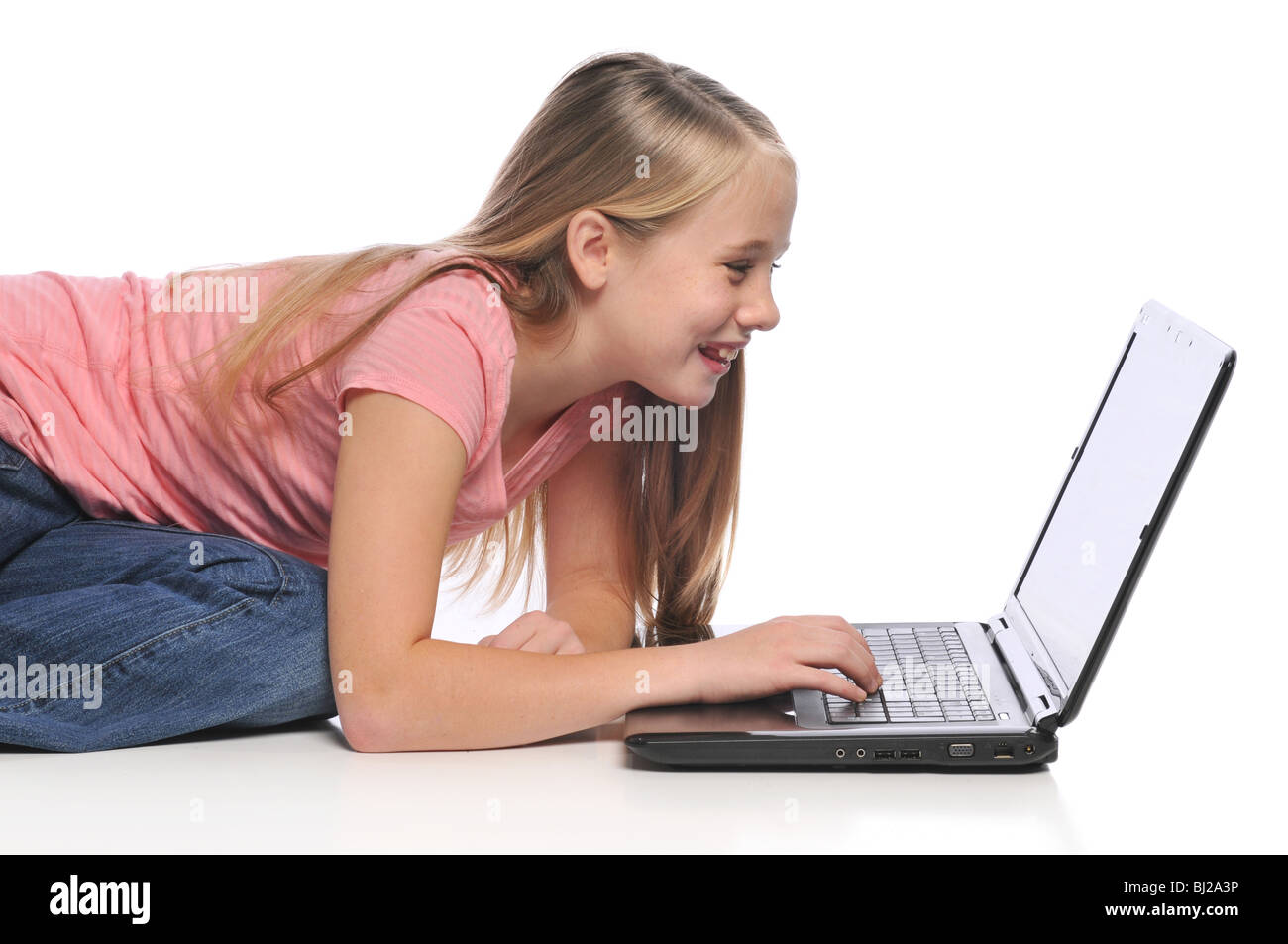 Young girl smiling working on a laptop isolated on white background ...