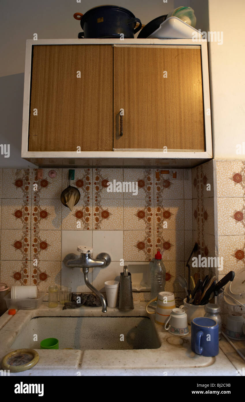 old crowded kitchen sink and cupboard in a dirty run down kitchen in ...